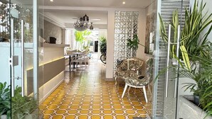 Entrada de hotel com tapete de boas-vindas exibindo "Casa Roman Hotel Boutique", área de recepção e espaço de refeições com cadeiras e mesas.