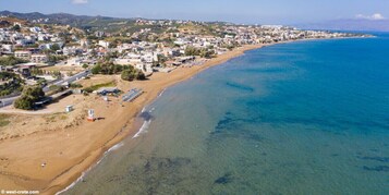 Vista aérea de uma cidade costeira com praia, águas azuis cristalinas e uma variedade de edifícios residenciais.