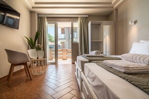 Quarto de hotel com cama, uma cadeira, uma mesinha com uma planta e uma televisão presa na parede.