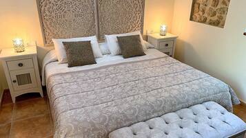 Quarto com uma cama grande, duas mesas de cabeceira, um criado-mudo e uma cabeceira decorativa.