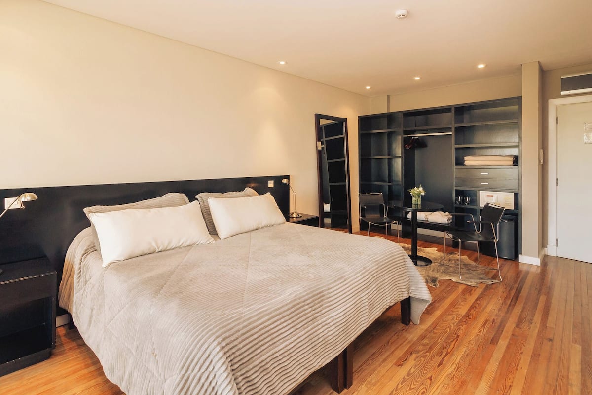 Quarto com cama grande, escrivaninha e guarda-roupa.