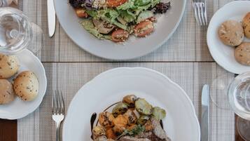 Uma mesa de jantar com dois pratos de comida, um garfo, uma faca e um copo de água.