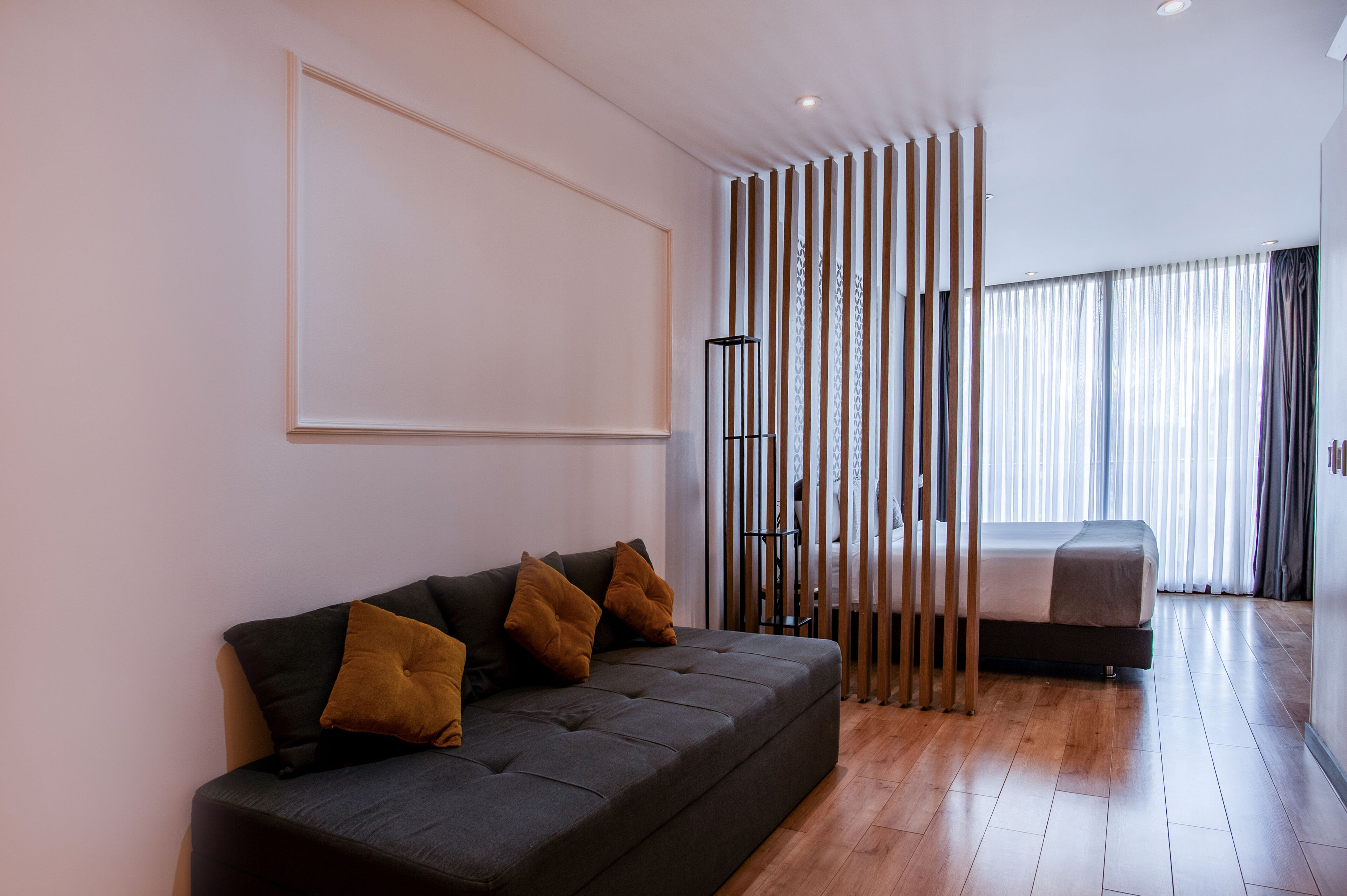 Quarto moderno com sofá, cama e uma janela grande com cortinas.