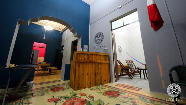 Um quarto com um divisória de madeira, uma porta vermelha e um tapete estampado.