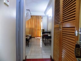 Corredor que dá para uma sala de jantar com mesa e cadeiras, uma cama e uma porta com chaveiro.