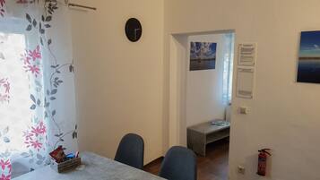 Quarto moderno com uma mesa de jantar, cadeiras, um relógio, um extintor de incêndio e vista para um lago pela janela.