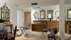 Uma área de refeições com mesa de mármore, cadeiras estofadas e um balcão de madeira com copos.