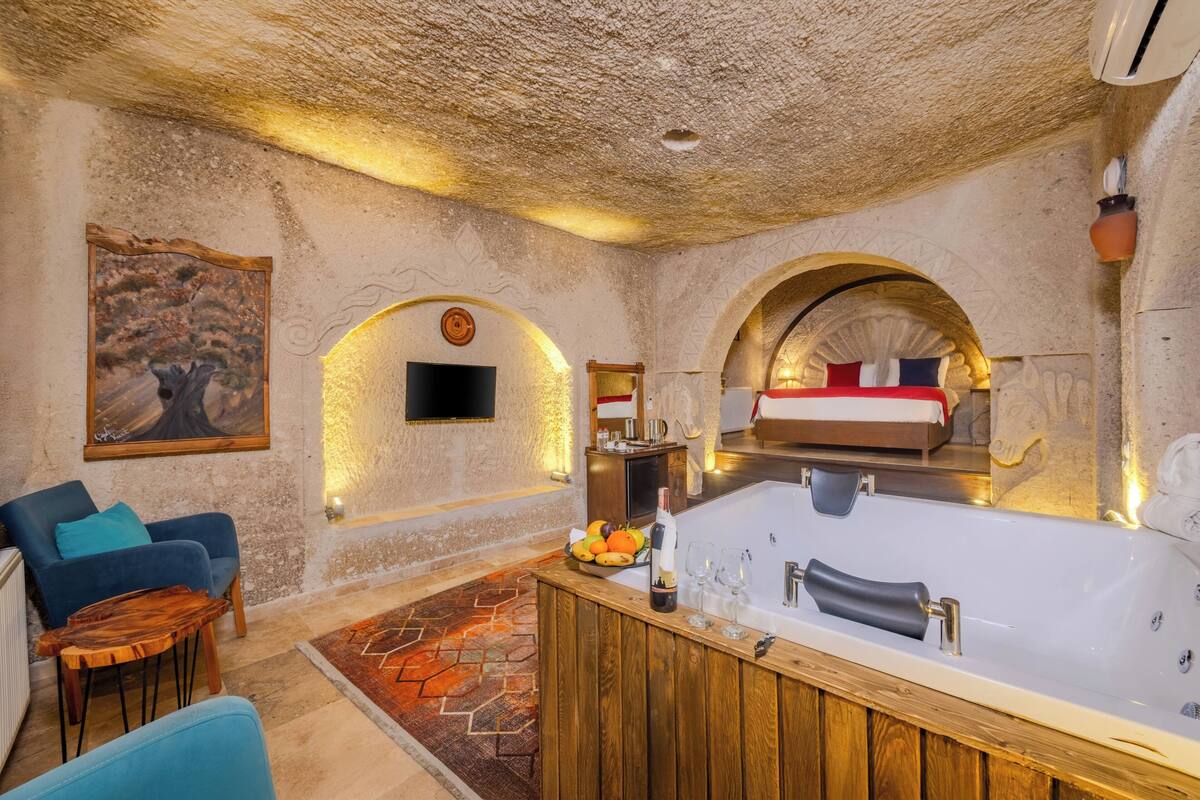 Um quarto com uma banheira grande, um balcão de madeira, um sofá e um quadro na parede.