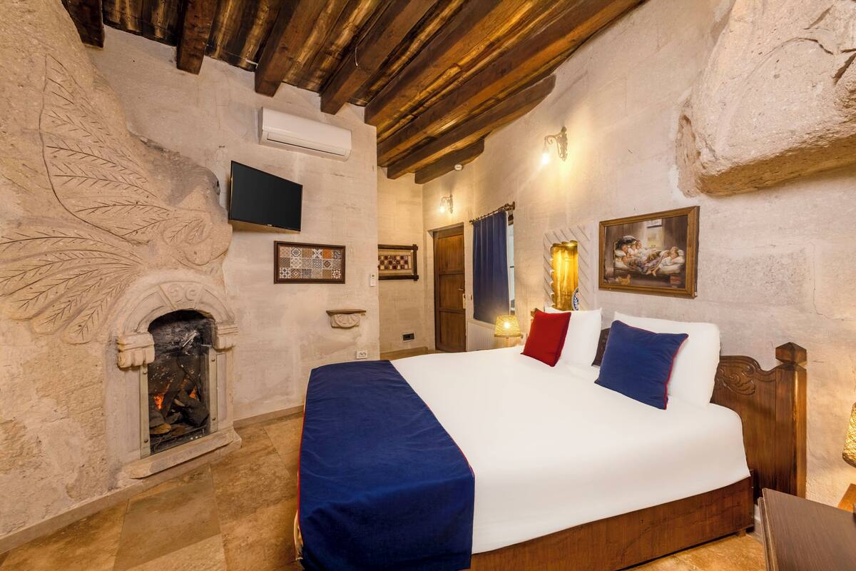 Quarto com uma cama grande, lareira e parede de pedra.