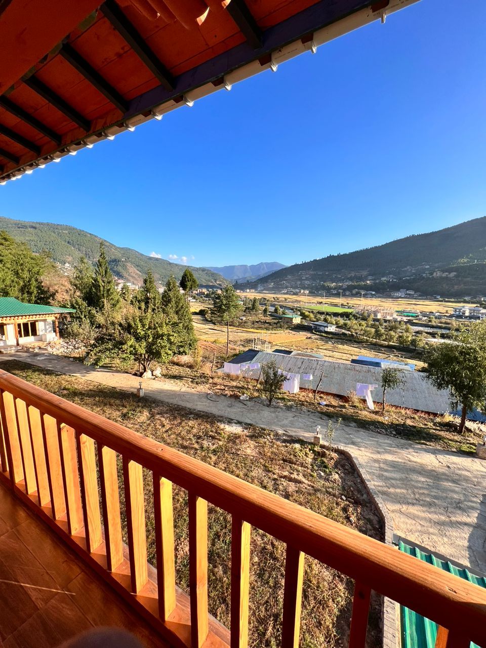 Varanda com vista para paisagem rural, incluindo campos e colinas ao longe.