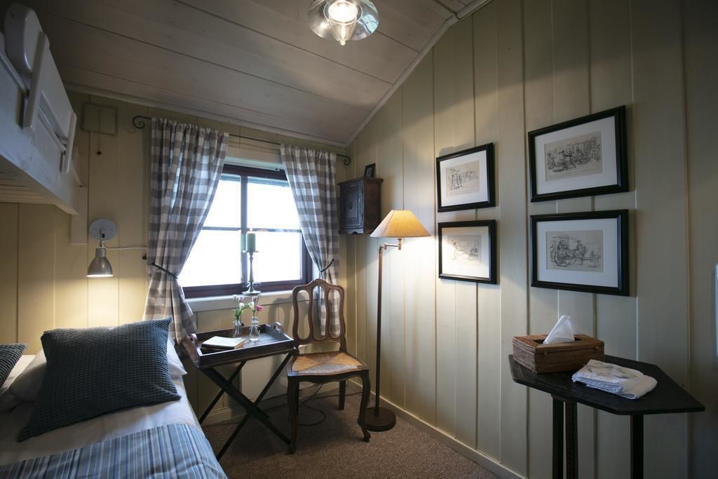 Quarto com cama, escrivaninha, cadeira, abajur e quadros na parede.
