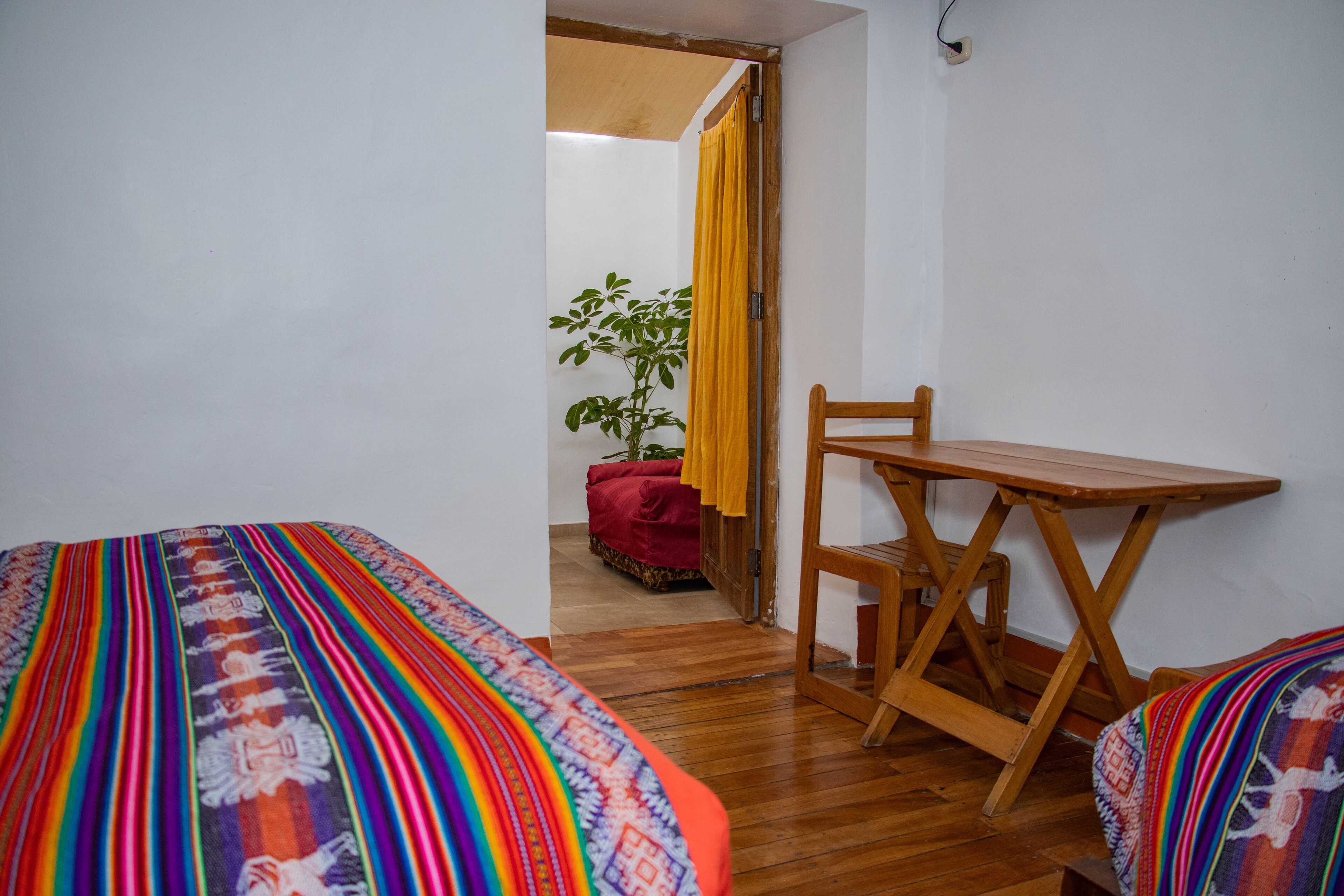 Quarto com duas camas, uma mesa de madeira e uma cadeira.