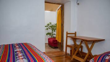 Quarto com duas camas, uma mesa de madeira e uma cadeira.
