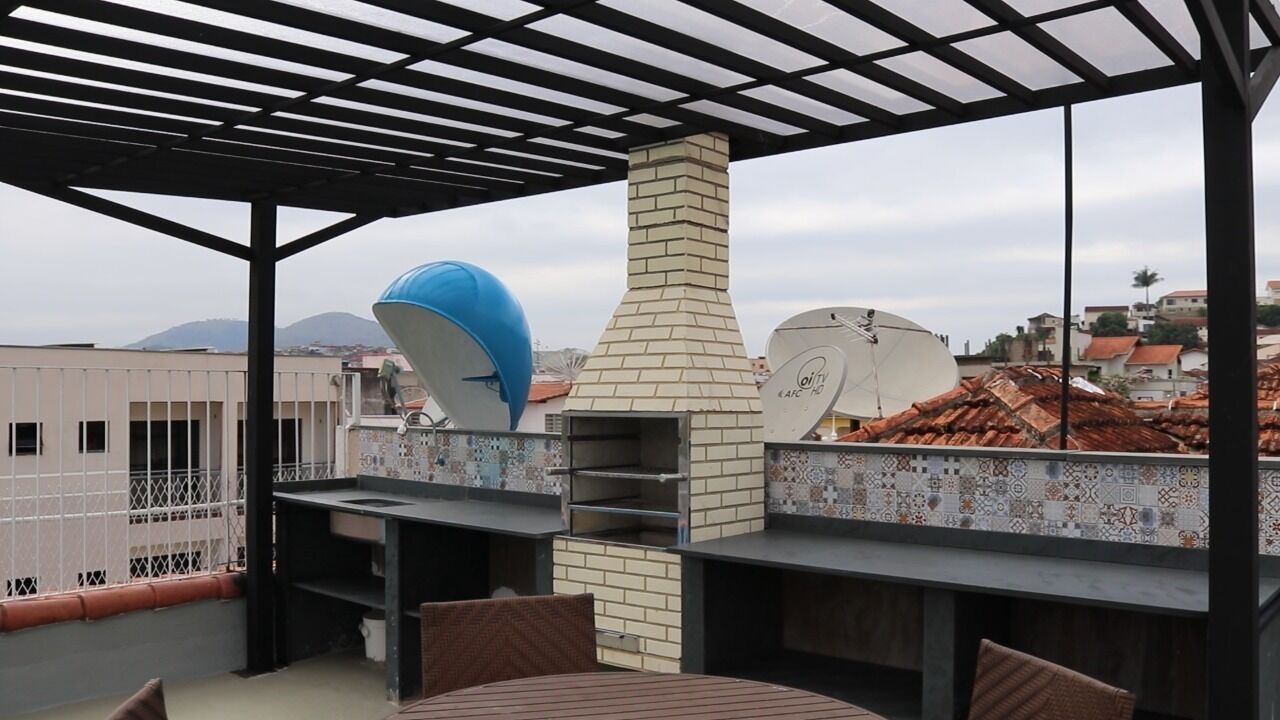 Um pátio externo com chaminé de tijolos, antena parabólica e mesa com cadeiras.