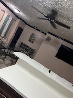 Quarto com ventoinha no teto, relógio, pintura e balcão branco.