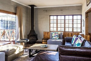 Uma sala de estar aconchegante com lareira, assentos confortáveis e uma grande janela com vista para uma paisagem deslumbrante.