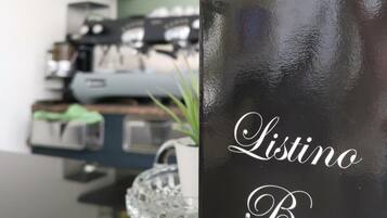 Painel de vidro preto com o texto 'Listino Bar' e um brasão com 'Restaurante Hotel Sica'.