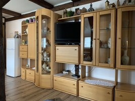 Um armário de madeira com portas de vidro, com objetos decorativos e uma televisão.