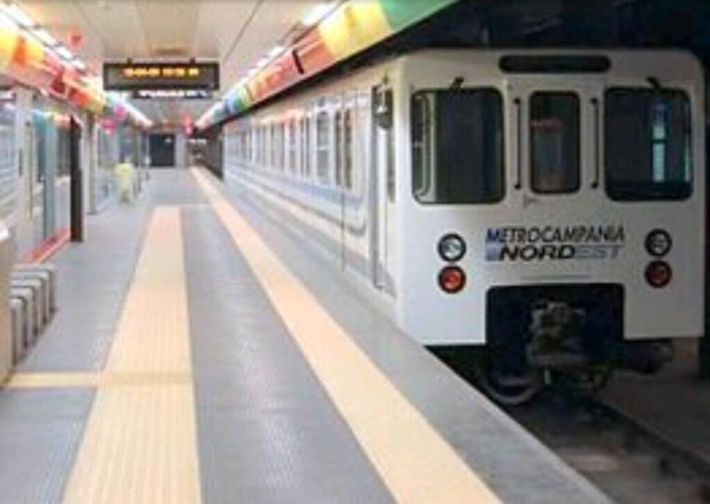 Um trem do metrô em uma plataforma de estação, com vista clara da lateral do trem e da borda da plataforma.