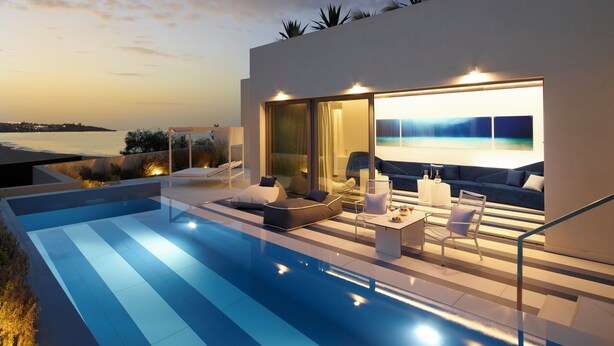 Uma área de estar moderna ao ar livre, com piscina, assentos e vista para o oceano ao entardecer.