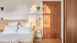Quarto com cama de madeira, porta de madeira e uma pequena mesa de cabeceira de madeira.
