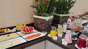 Buffet com diversas frutas, sucos e sobremesas.