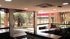 Uma área de recepção com balcão, assentos e grandes janelas com vista para o exterior.