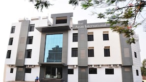 Um edifício de hotel moderno com fachada de vidro destacada, várias varandas e uma placa com a inscrição 
