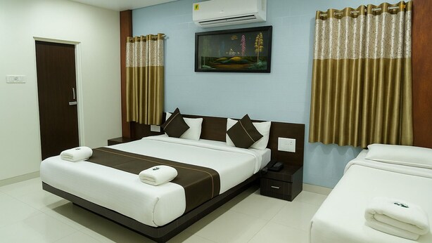 Quarto de hotel com cama, mesas de cabeceira, ar condicionado, um quadro e cortinas.