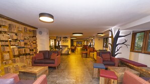 Um hall amplo com mobiliário de madeira, um balcão de recepção e uma parede com um desenho de árvore.