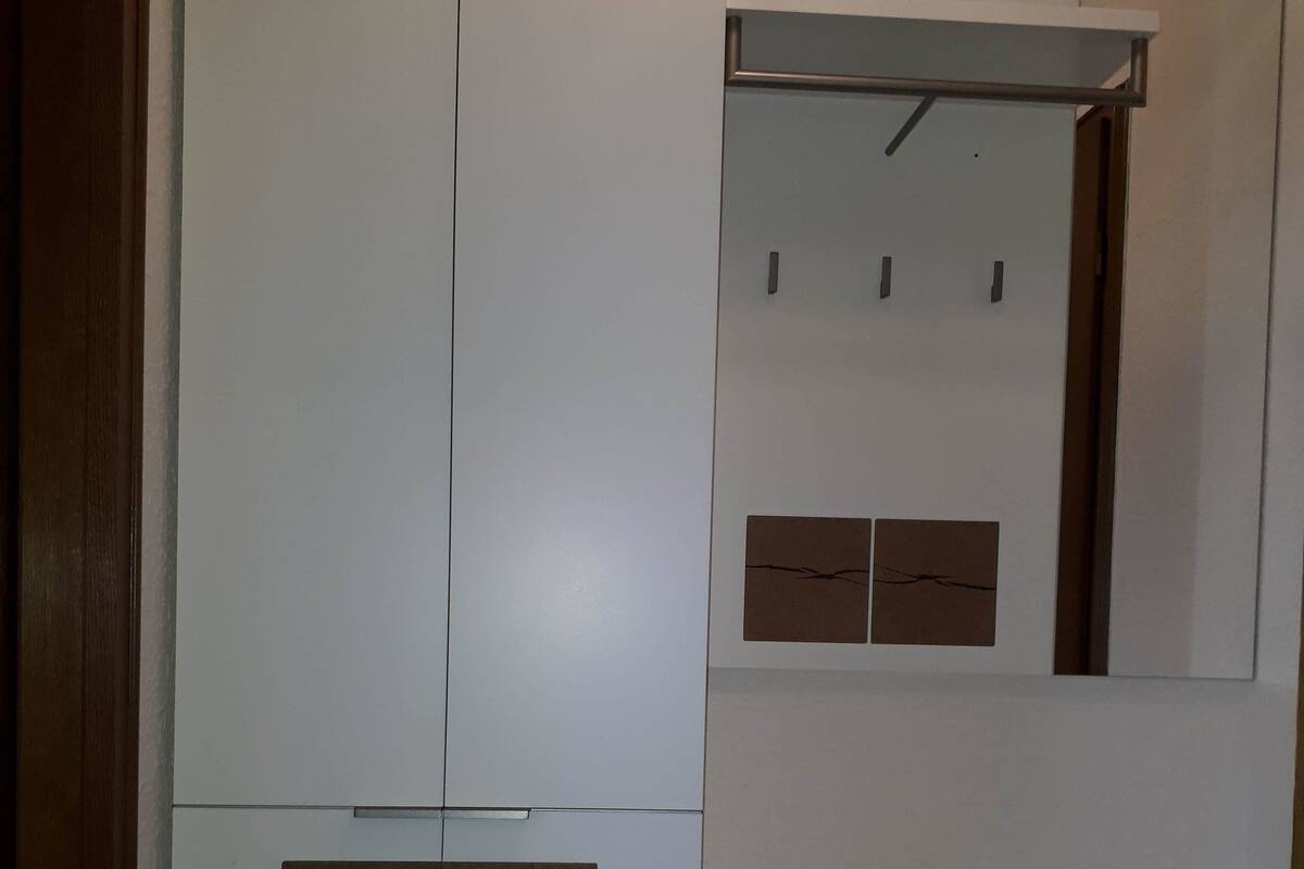Casa de banho com guarda-roupa branco, espelho e porta-toalhas.