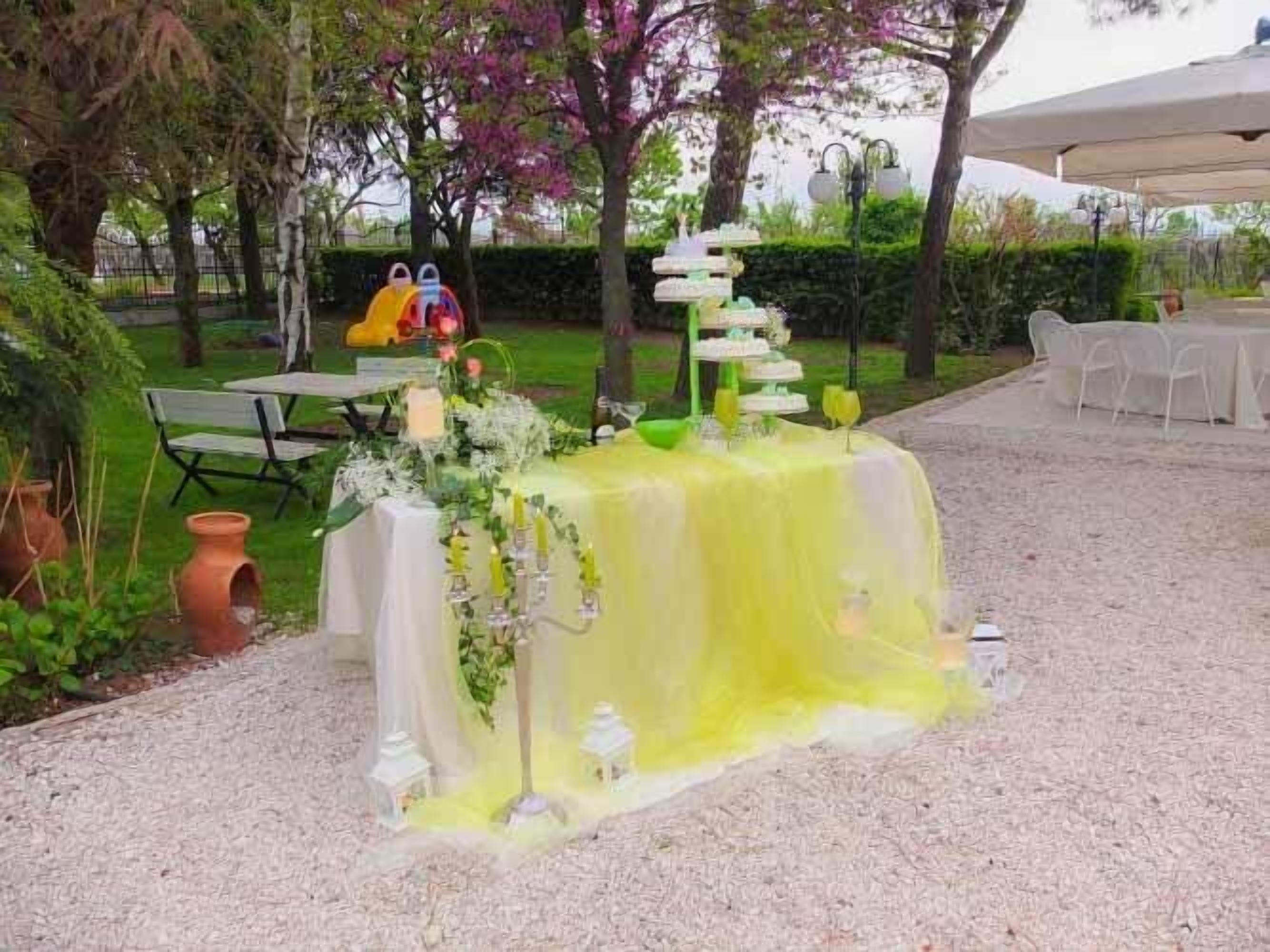 Montagem de casamento ao ar livre com mesa coberta, cadeiras e arranjo floral.