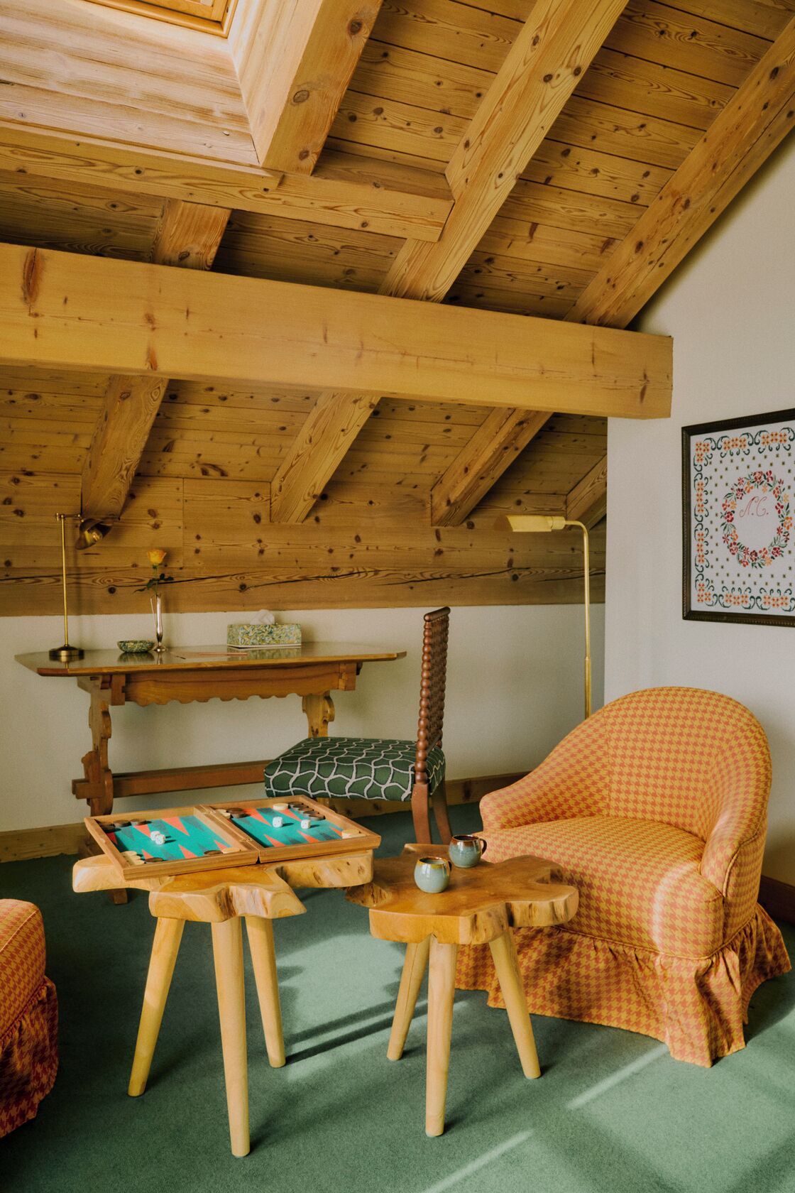 Quarto acolhedor com vigas de madeira, cama de madeira, uma cadeira, uma mesa e um quadro na parede.