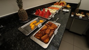 Buffet com diversos alimentos, incluindo frutas, legumes e frituras.