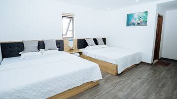 Quarto de hotel com duas camas, uma janela, um quadro e chão de madeira.