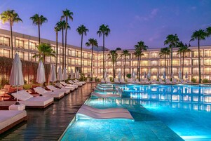 Um hotel com piscina, espreguiçadeiras e palmeiras.