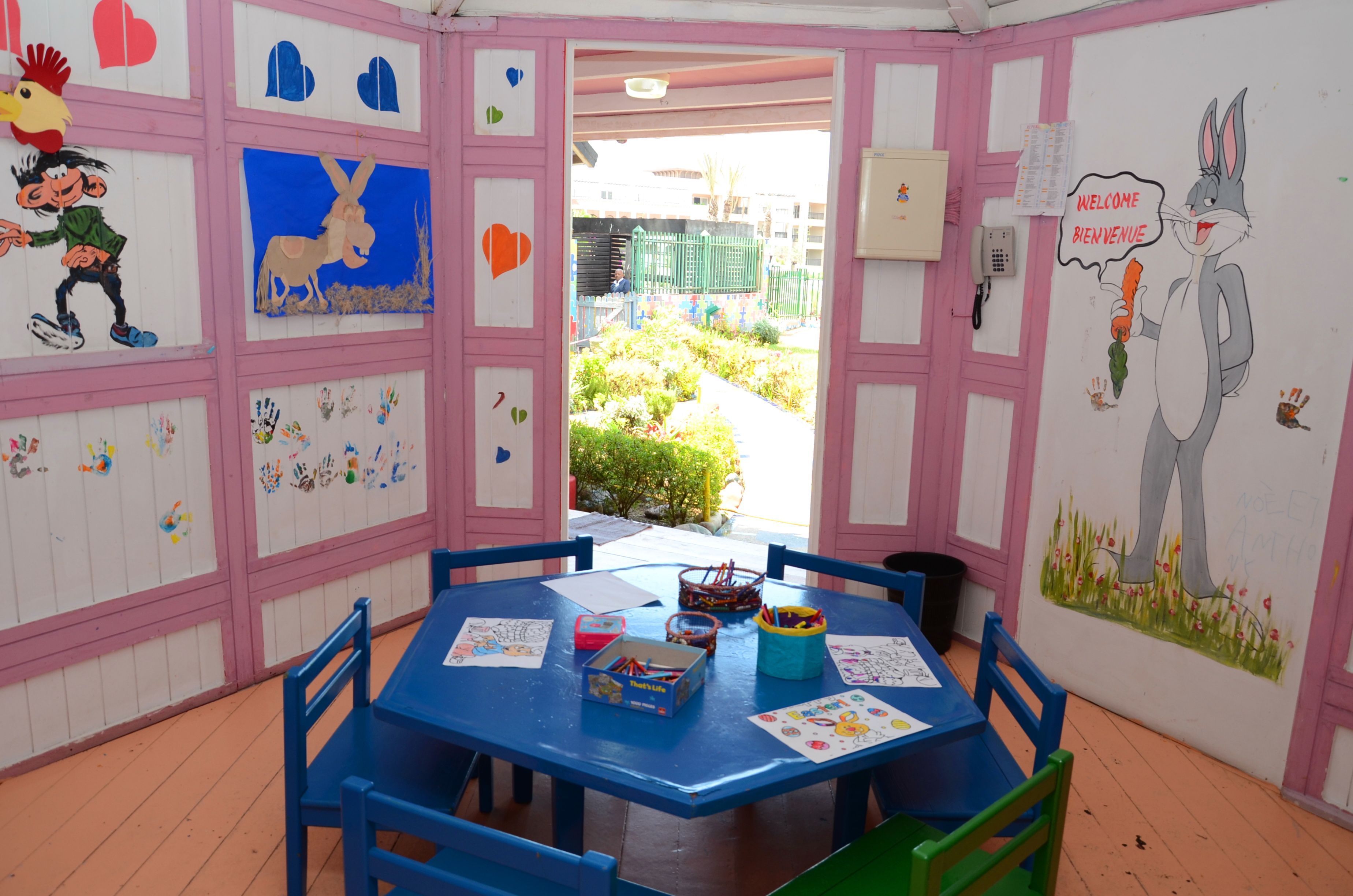 Quarto infantil com mesa, cadeiras e decorações coloridas nas paredes.