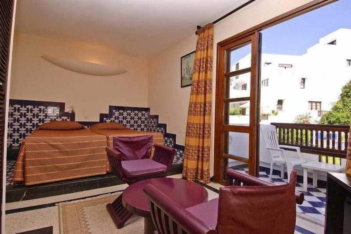 Quarto de hotel com duas camas, uma varanda e vista para edifícios.