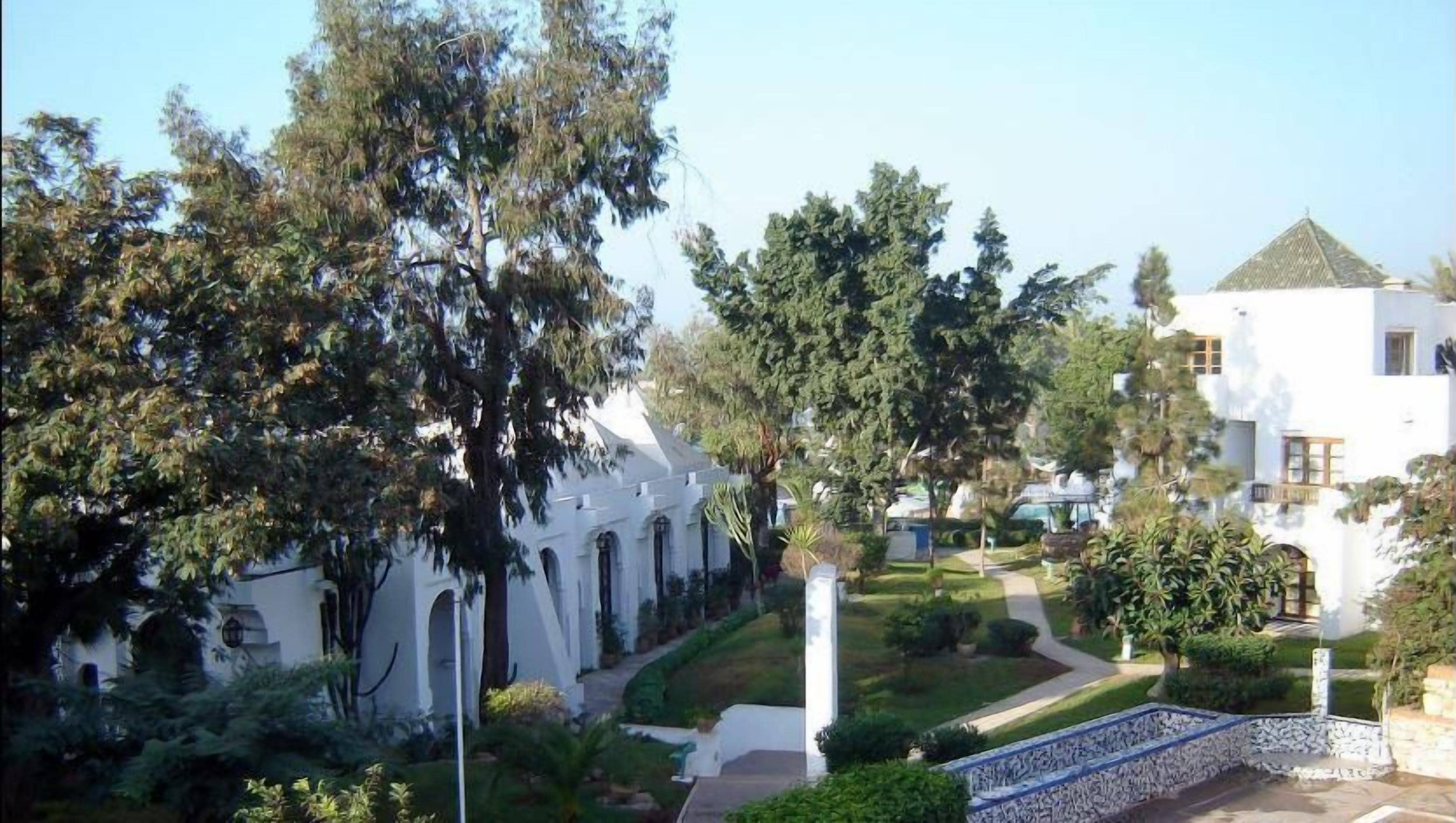 Um edifício branco com janelas em arco e um pátio central com uma fonte.