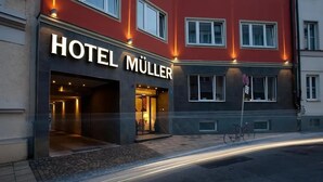 Um hotel chamado "HOTEL MÜLLER", com fachada moderna e letreiros iluminados.