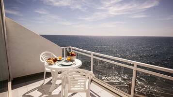 Varanda com mesa posta para o café da manhã, com vista para um corpo d'água.