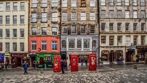 Uma rua histórica com arquitetura tradicional, incluindo uma loja de fábrica da Royal Mile e uma loja Woolfied.