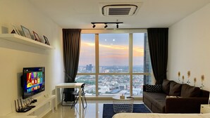 Quarto de hotel moderno com uma grande janela com vista para a cidade, TV de tela plana, sofá e área de jantar.