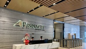 Recepção de um hotel Pinnacle Petaling Jaya, com balcão de mármore, arranjo floral e design moderno no teto.