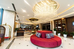 Um hall moderno com um sofá vermelho, um lustre grande e um balcão de recepção.