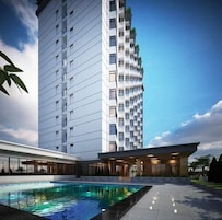 Um hotel moderno com piscina, um edifício alto com varandas e céu claro.