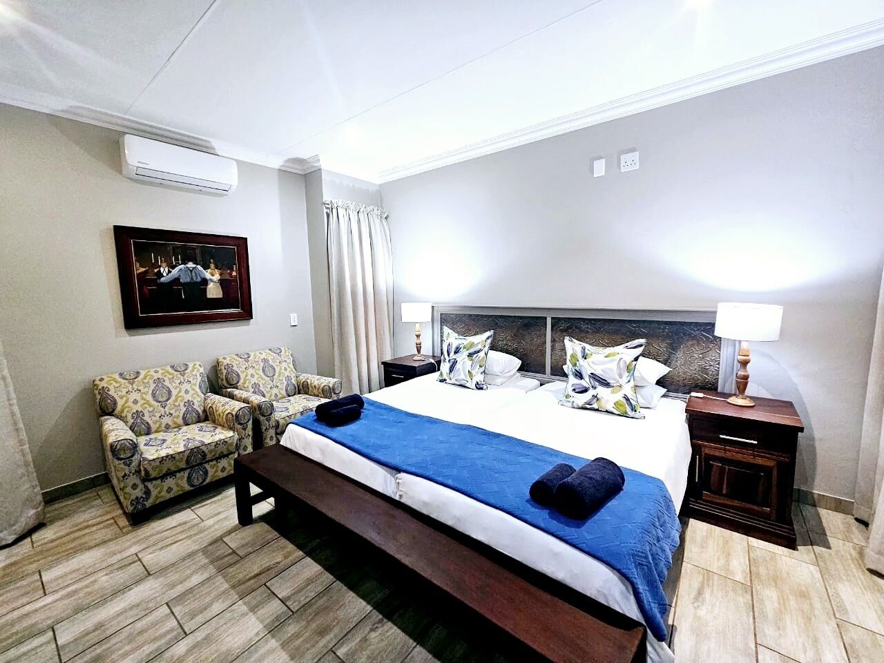 Quarto de hotel com uma cama grande, um sofá, uma mesa de cabeceira e um aparelho de ar condicionado.