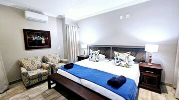 Quarto de hotel com uma cama grande, um sofá, uma mesa de cabeceira e um aparelho de ar condicionado.