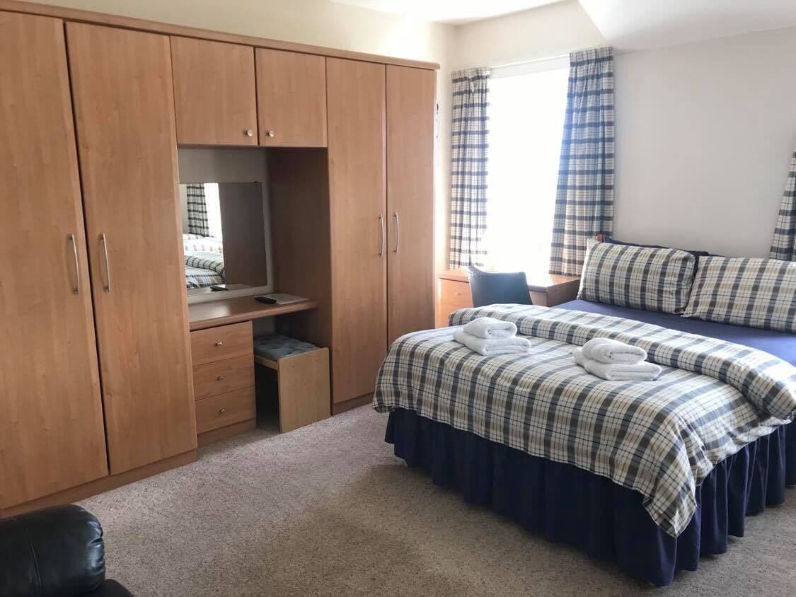 Quarto com cama, escrivaninha e guarda-roupa.
