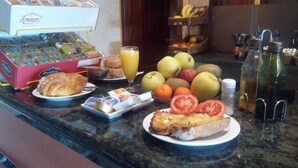 Uma mesa de pequeno-almoço com pastelaria, fruta e sumo.